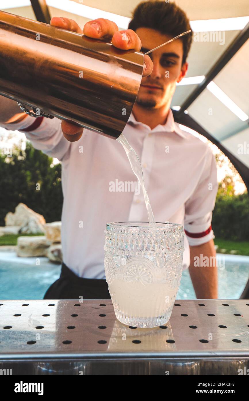 Vertical shot of a Caucasian bartender making cocktails at the venue of ...