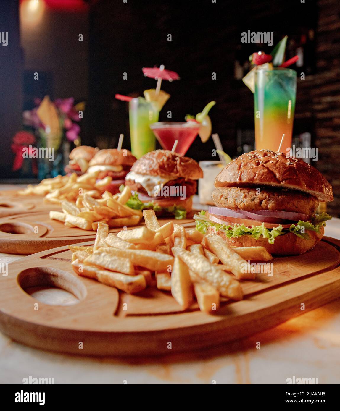 Vertical shot of fast food with cocktails on wooden cutting boards ...