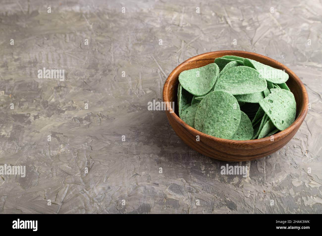 green potato chips with herbs in wooden bowl on gray concrete ...