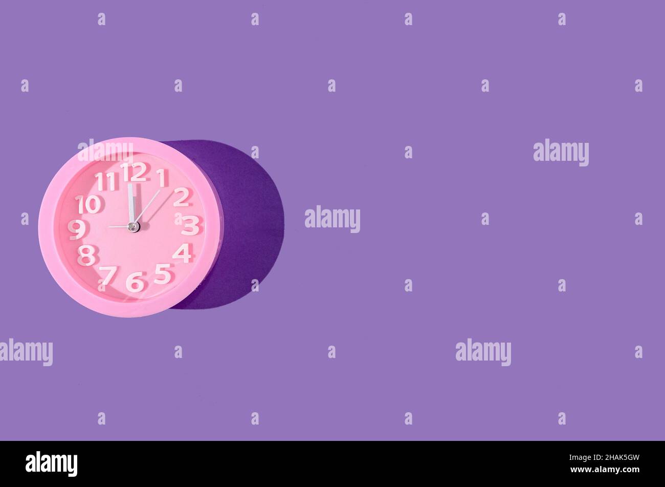 A pink clock showing midnight on violet background. Minimal concept for ...