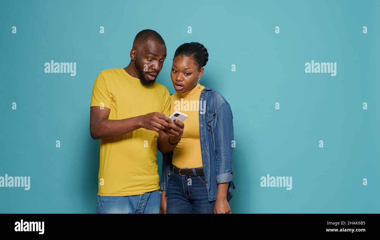 Man and woman using internet on smartphone together in front of camera ...