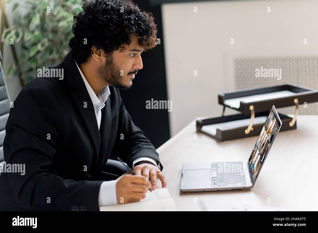 Focused young adult smart successful Indian businessman in formal suit ...