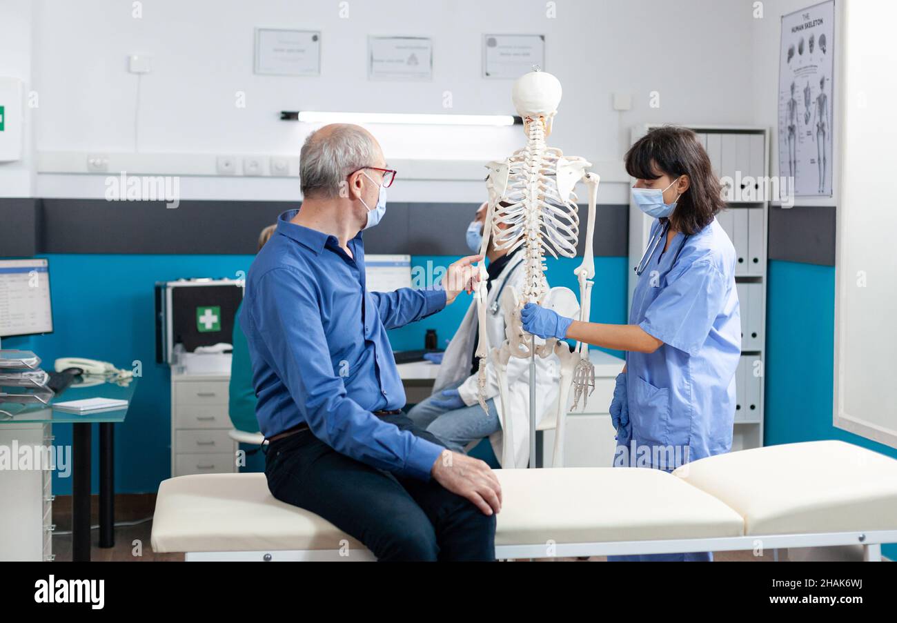 Patient and nurse with face masks looking at spine bones on human ...