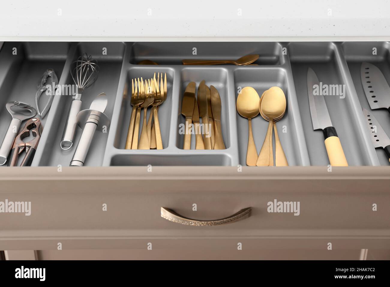 Open kitchen drawer with golden cutlery and utensils, closeup Stock ...