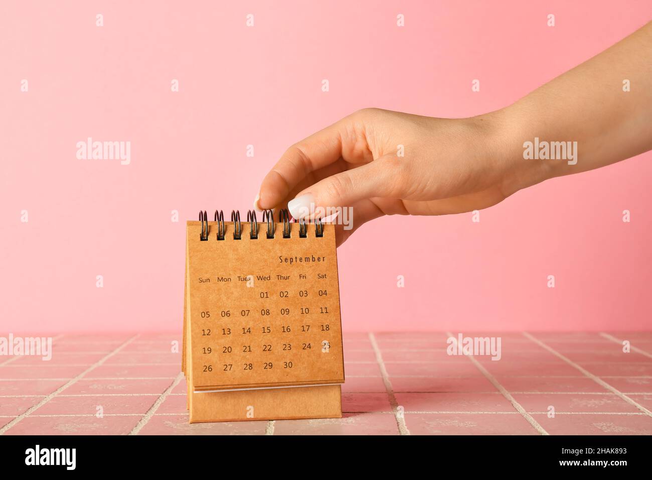 Female hand with craft calendar on pink background Stock Photo - Alamy