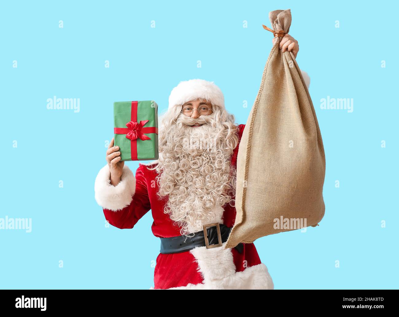 Santa Claus with sack bag and present on blue background Stock Photo ...