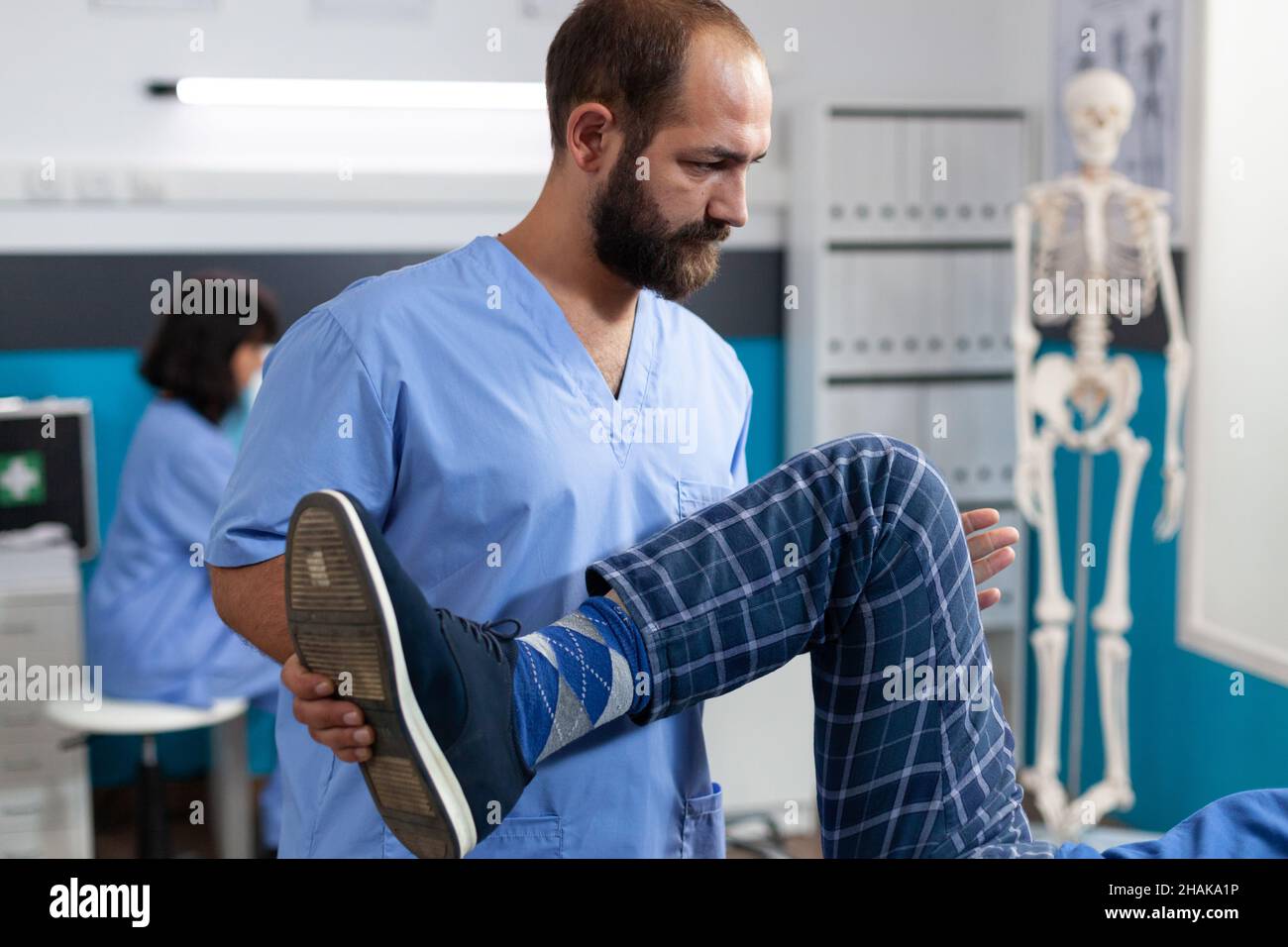 Chiropractor stretching leg of retired patient for physiotherapy ...