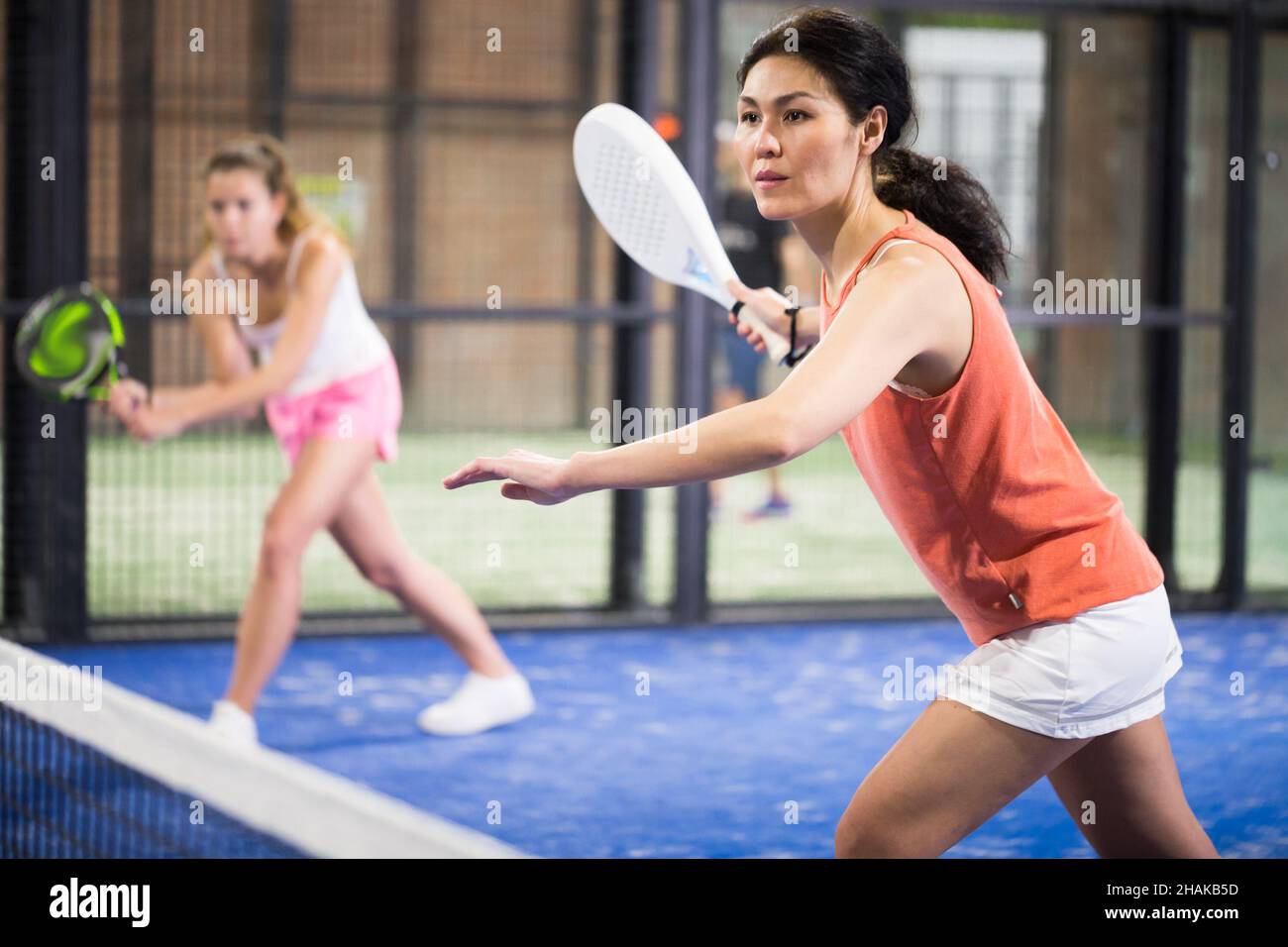 Portrait of sporty adult asian woman playing padel on indoor court ...