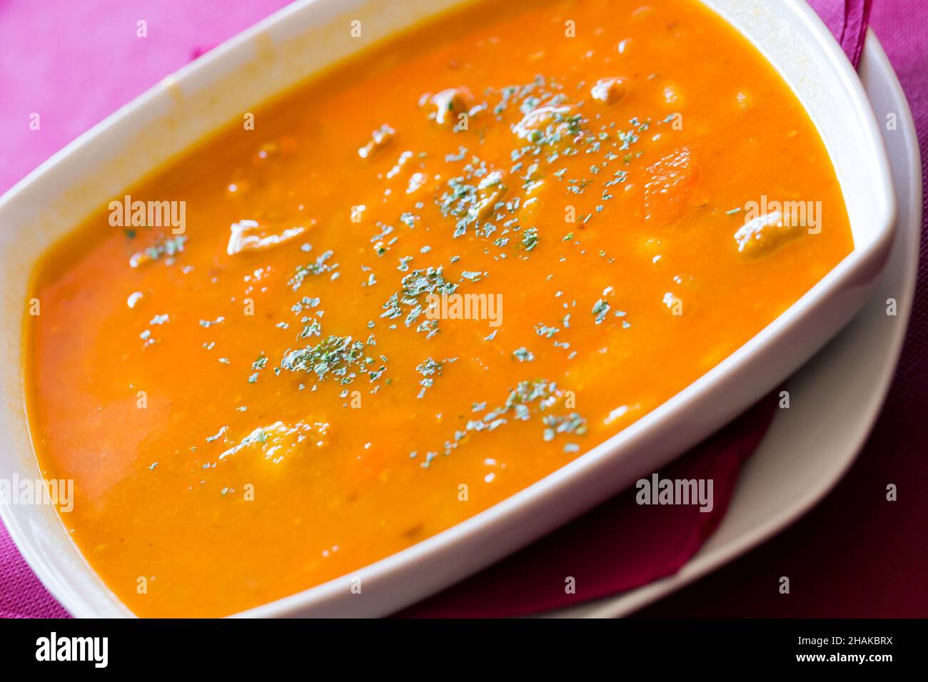Traditional Spanish stew of beans with pig ears served in white bowl ...