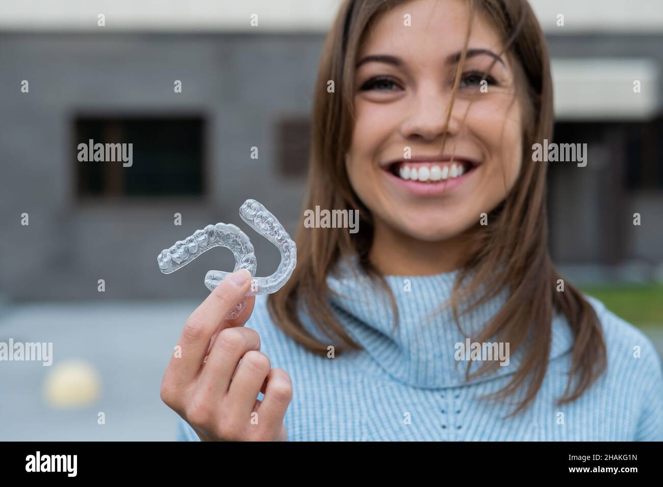 Caucasian woman with white smile holding transparent removable retainer ...