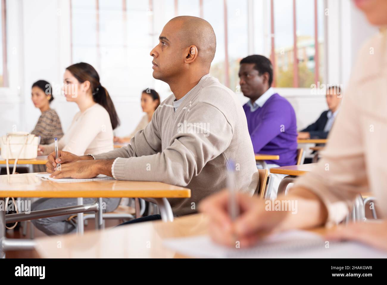 Portrait of focused young adult male studying in classroom with ...