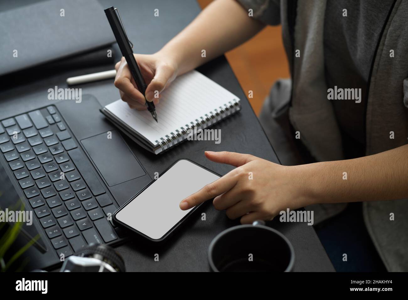 A female taking notes on notepad while looking an informations on ...