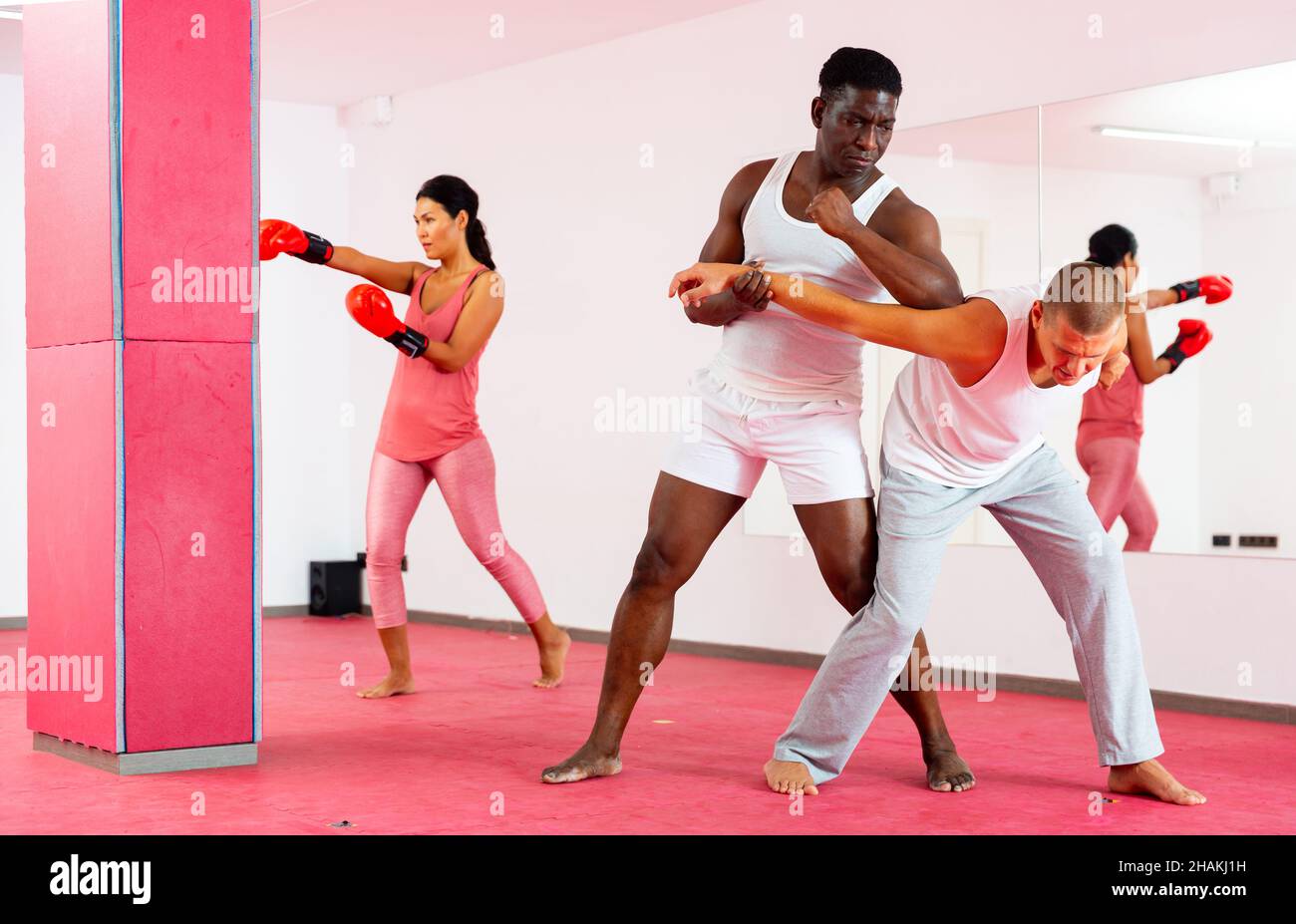 African-american and European men exercising joint lock in gym. Asian ...