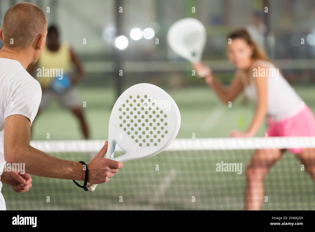 Padel player playing padel in a padel court indoor behind the net Stock ...