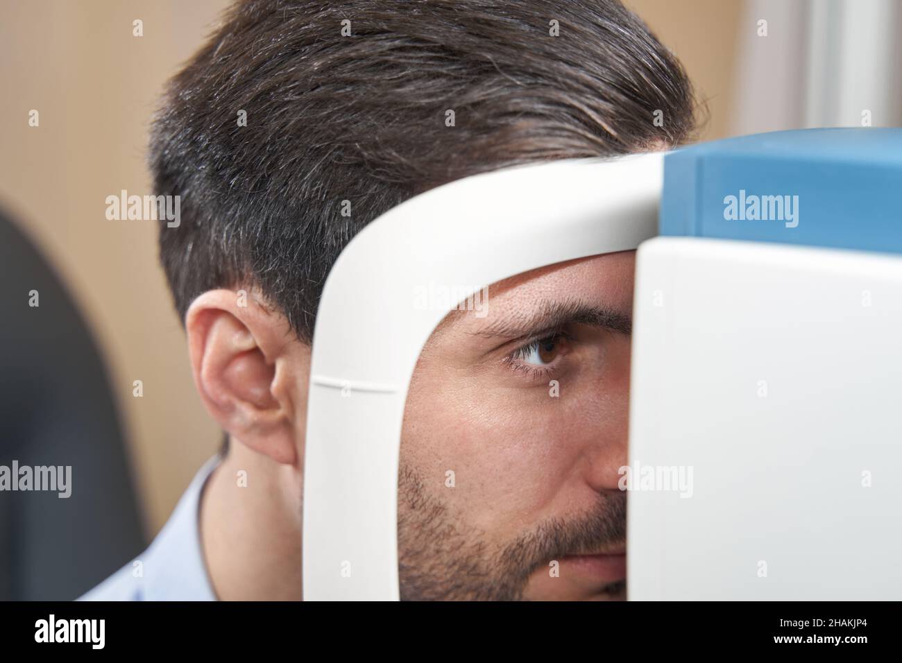 Male patient looking into autorefractor during eye inspection Stock ...