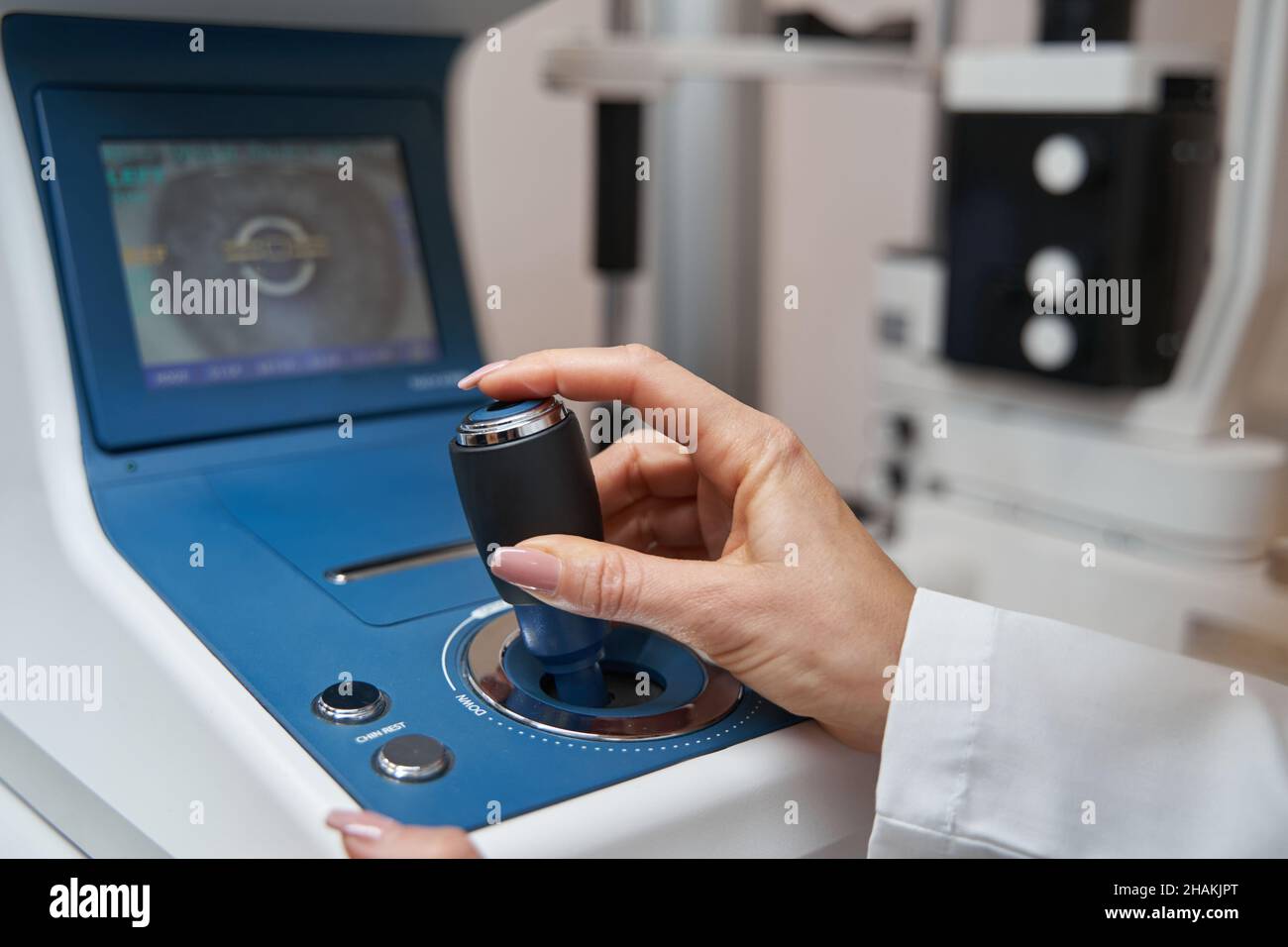 Doctor using joystick of automated refractor during eye diagnostics ...