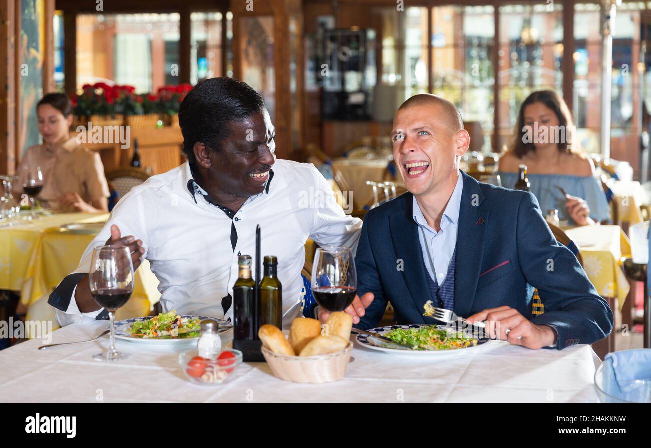 Two cheerful male friends at dinner in restaurant Stock Photo - Alamy