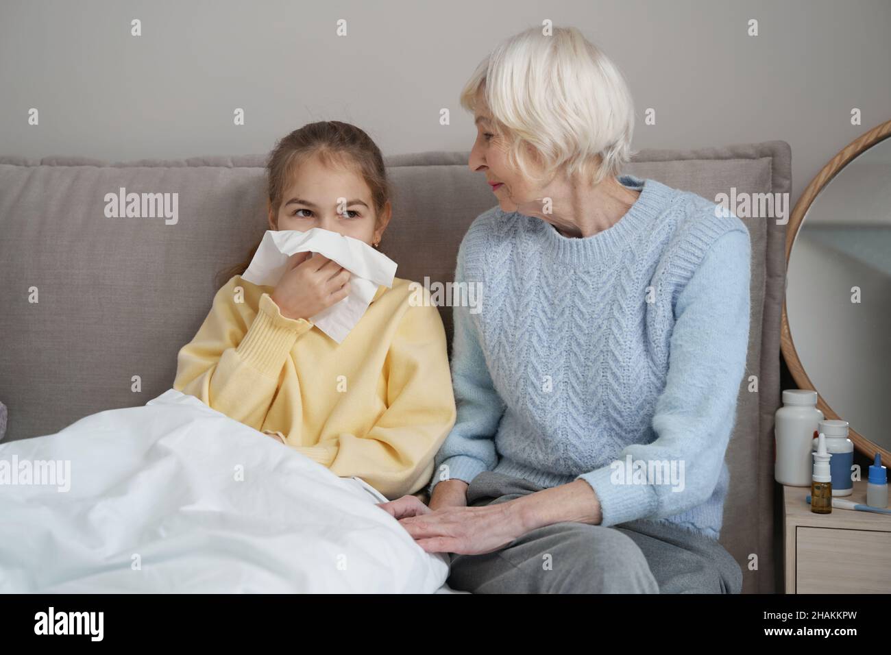 Supportive elderly lady sitting beside her sick granddaughter Stock ...