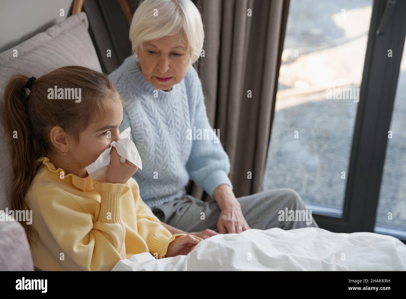 Worried grandma taking care of a sick kid in bed Stock Photo - Alamy