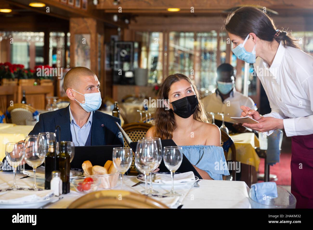 Positive young couple making order at restaurant Stock Photo - Alamy