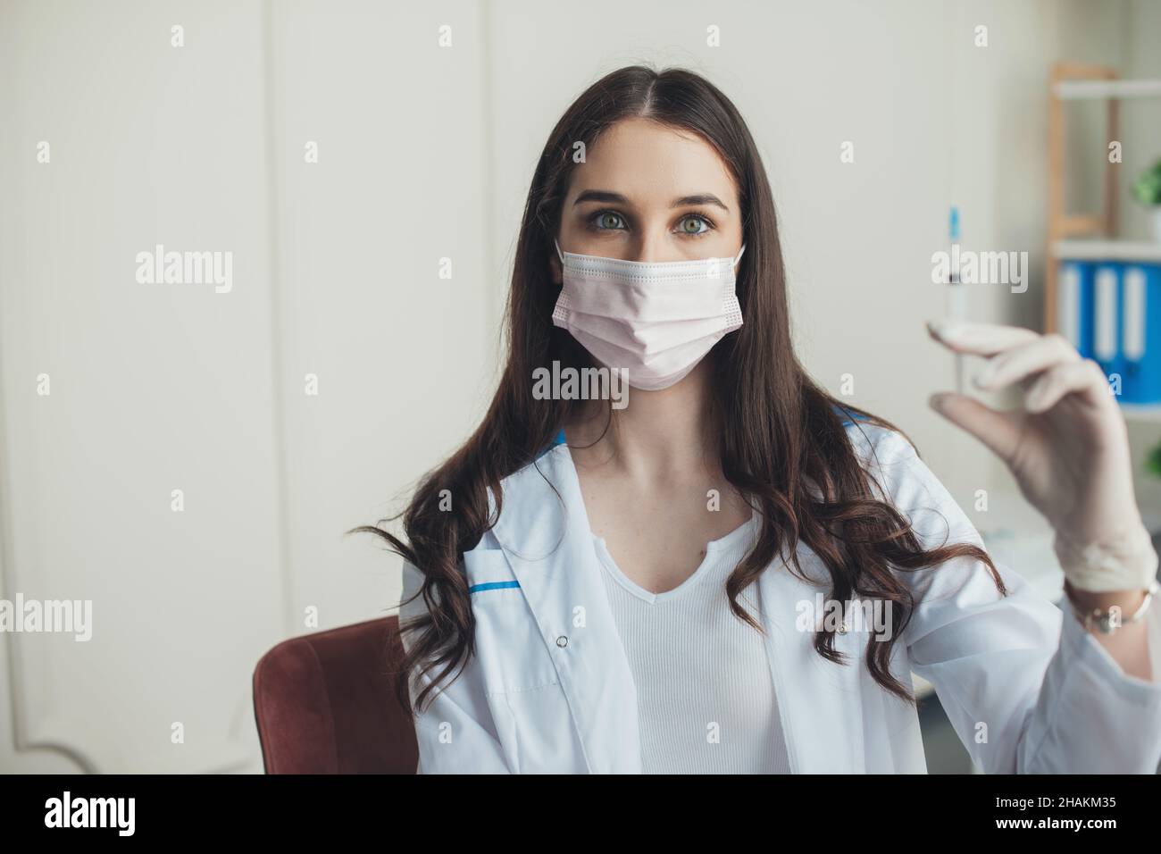 Nurse posing with syringe for vaccine injection wearing white robe ...