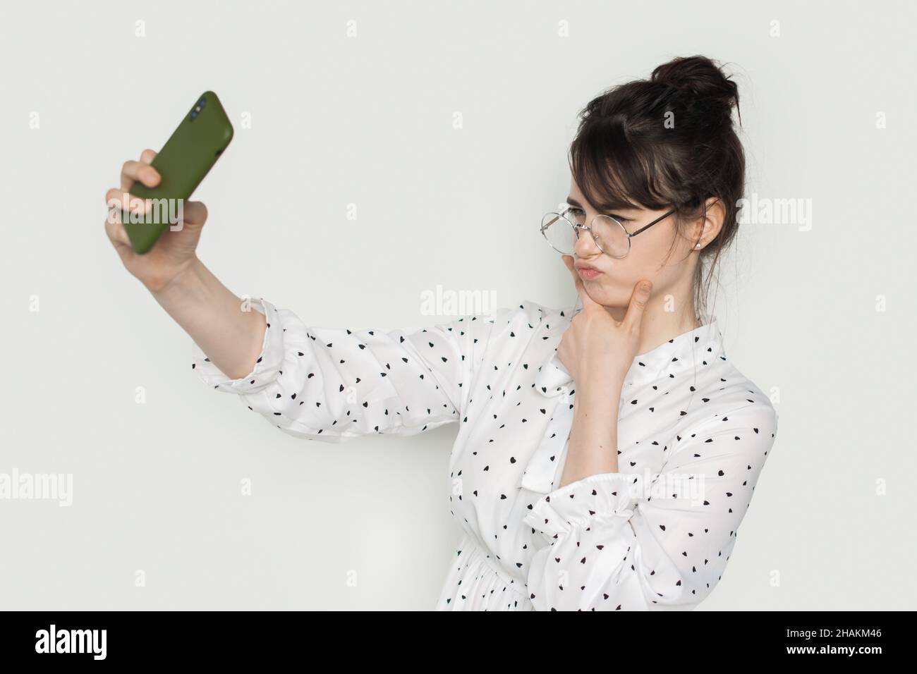 Side view of a student making a duck face and taking a self portrait ...