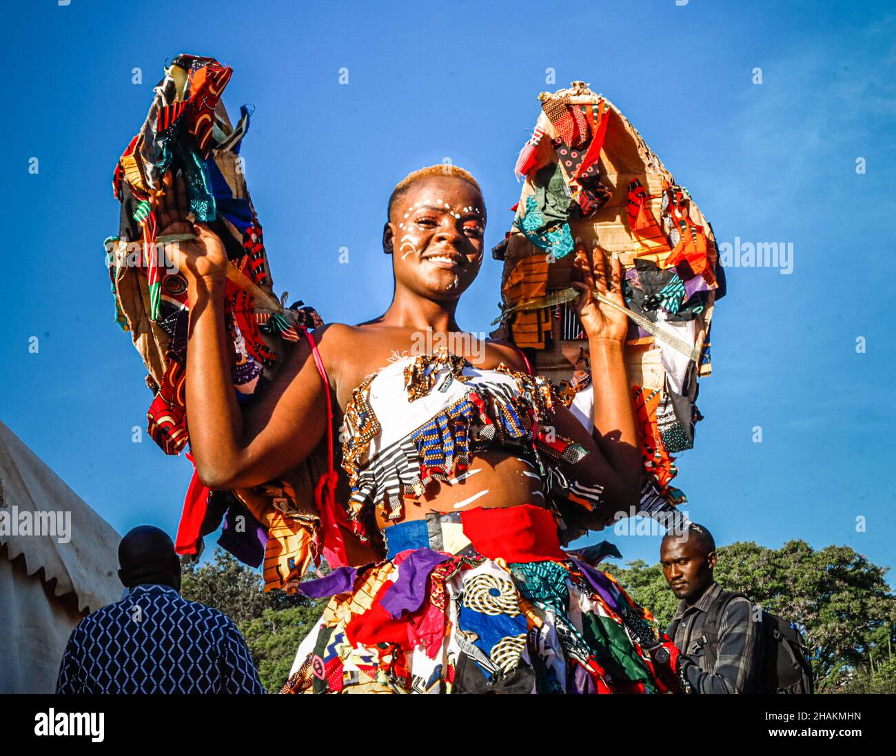 A young female model dressed in a colorful outfit poses by the streets ...