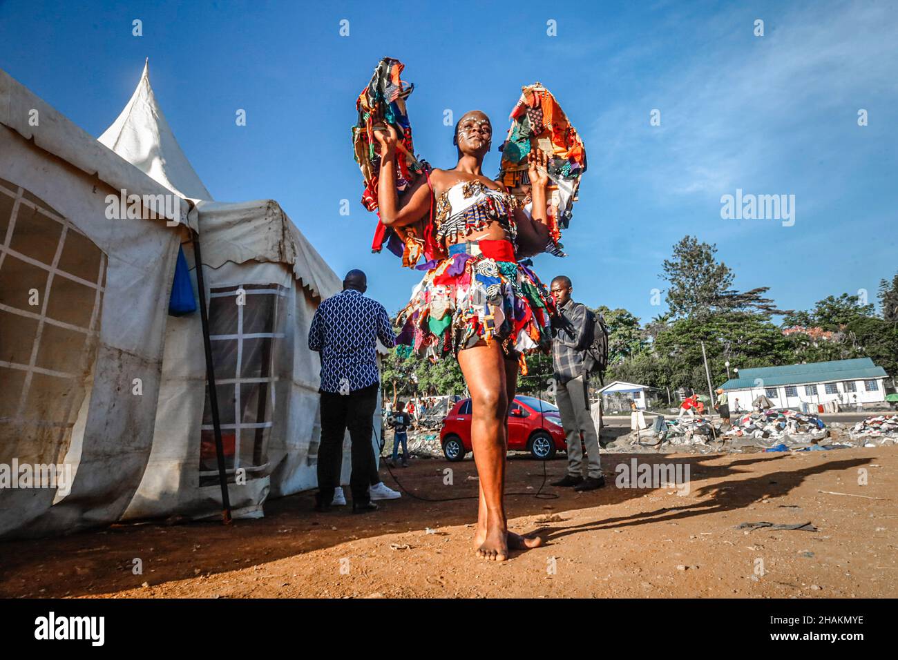A young female model dressed in a colorful outfit poses by the streets ...