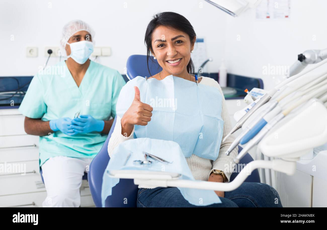 Smiling female patient showing thumb in dental clinic Stock Photo - Alamy
