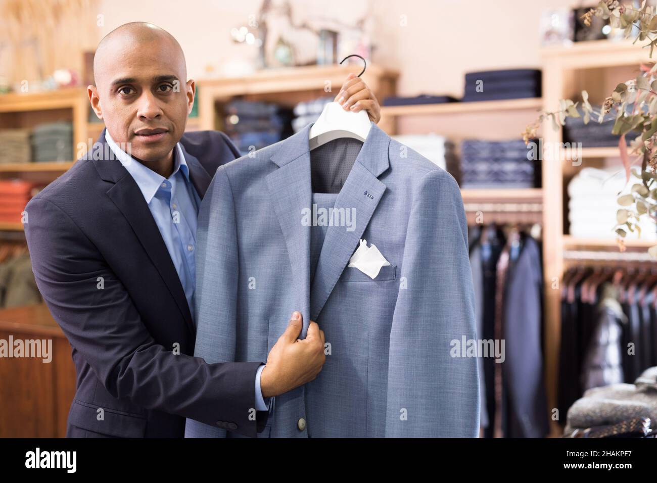 Friendly salesman offering suit in menswear boutique Stock Photo - Alamy