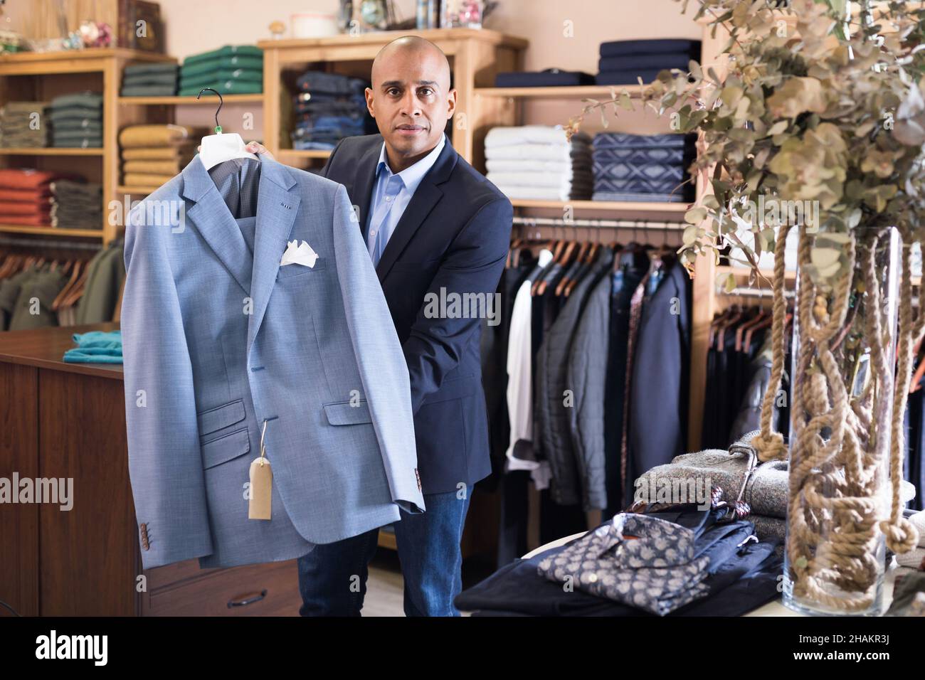 Friendly salesman offering suit in menswear boutique Stock Photo - Alamy