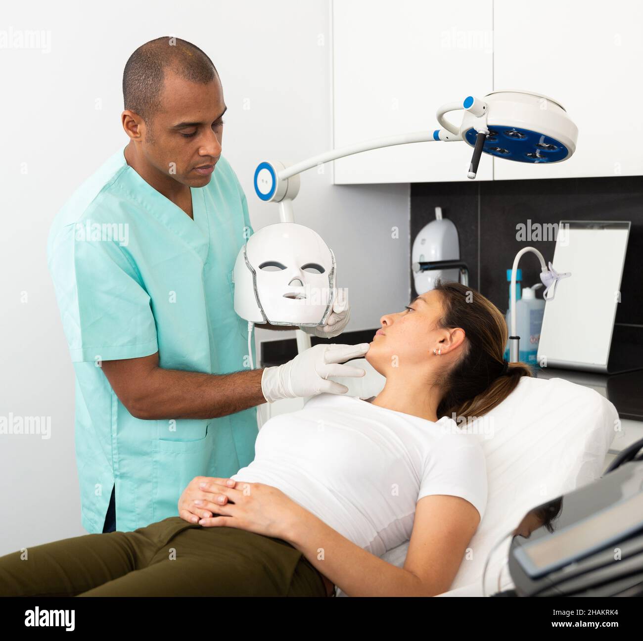 Cosmetician explaining phototherapy procedure to female client Stock ...