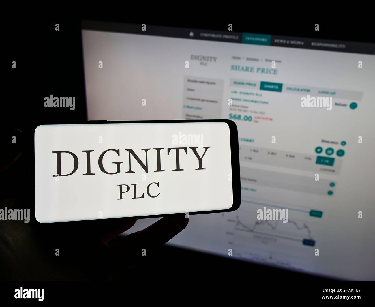 Person holding mobile phone with logo of funeral services company ...