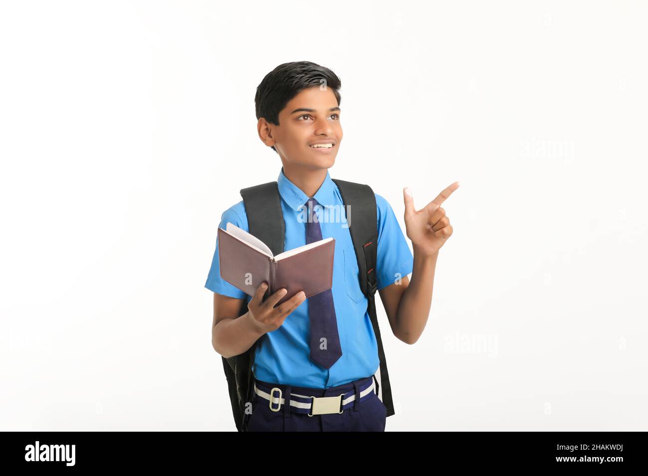 Indian school boy in uniform and reading diary on white background ...