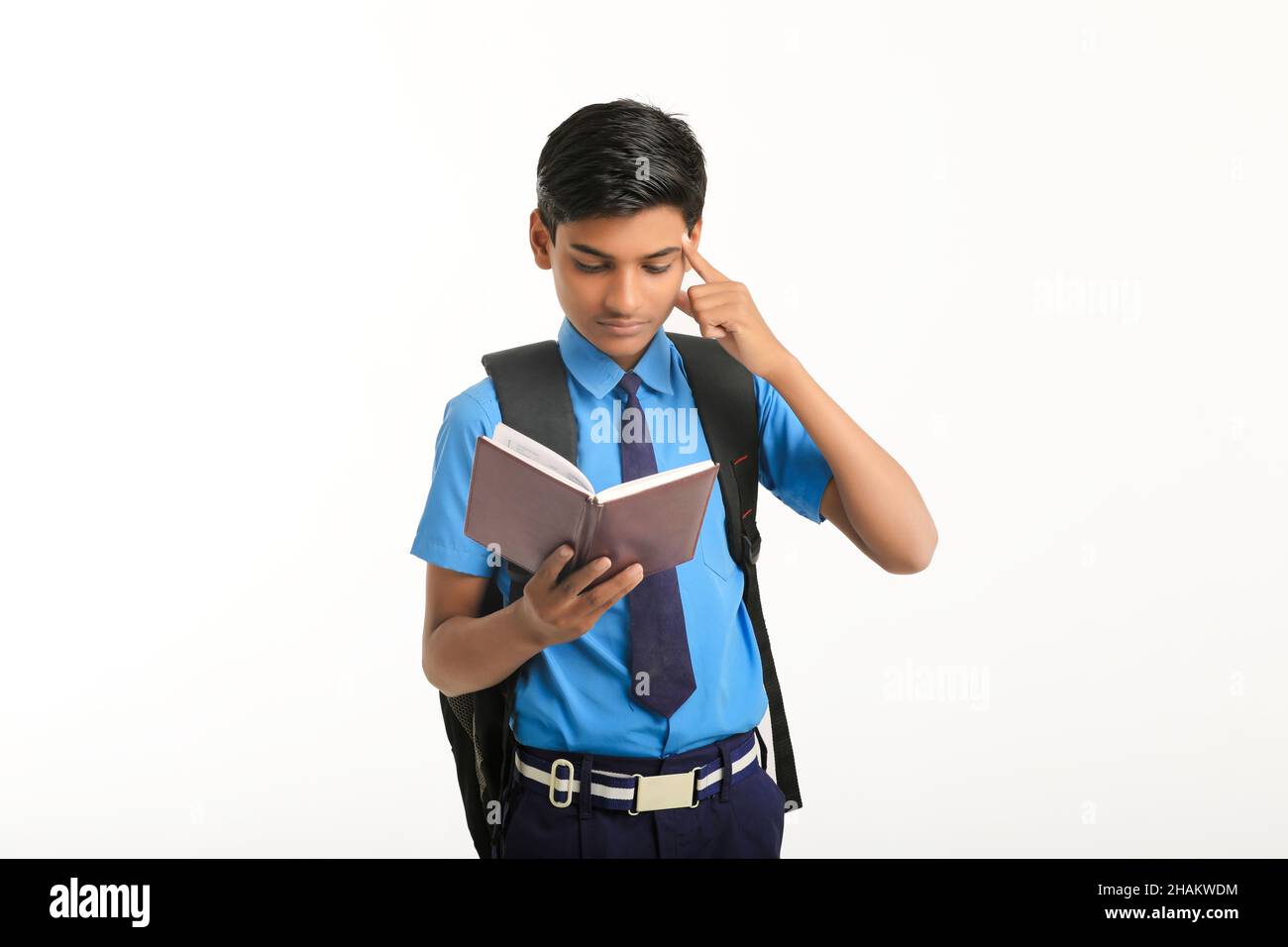 Indian school boy in uniform and reading diary on white background ...