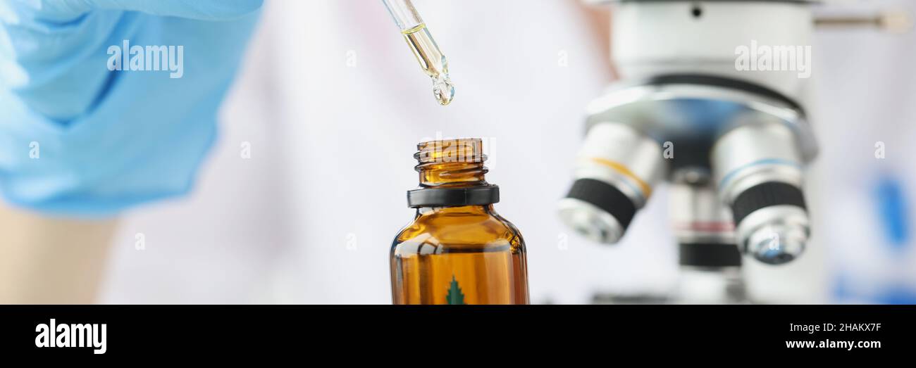 Scientist chemist examining marijuana oil under microscope in lab clo ...