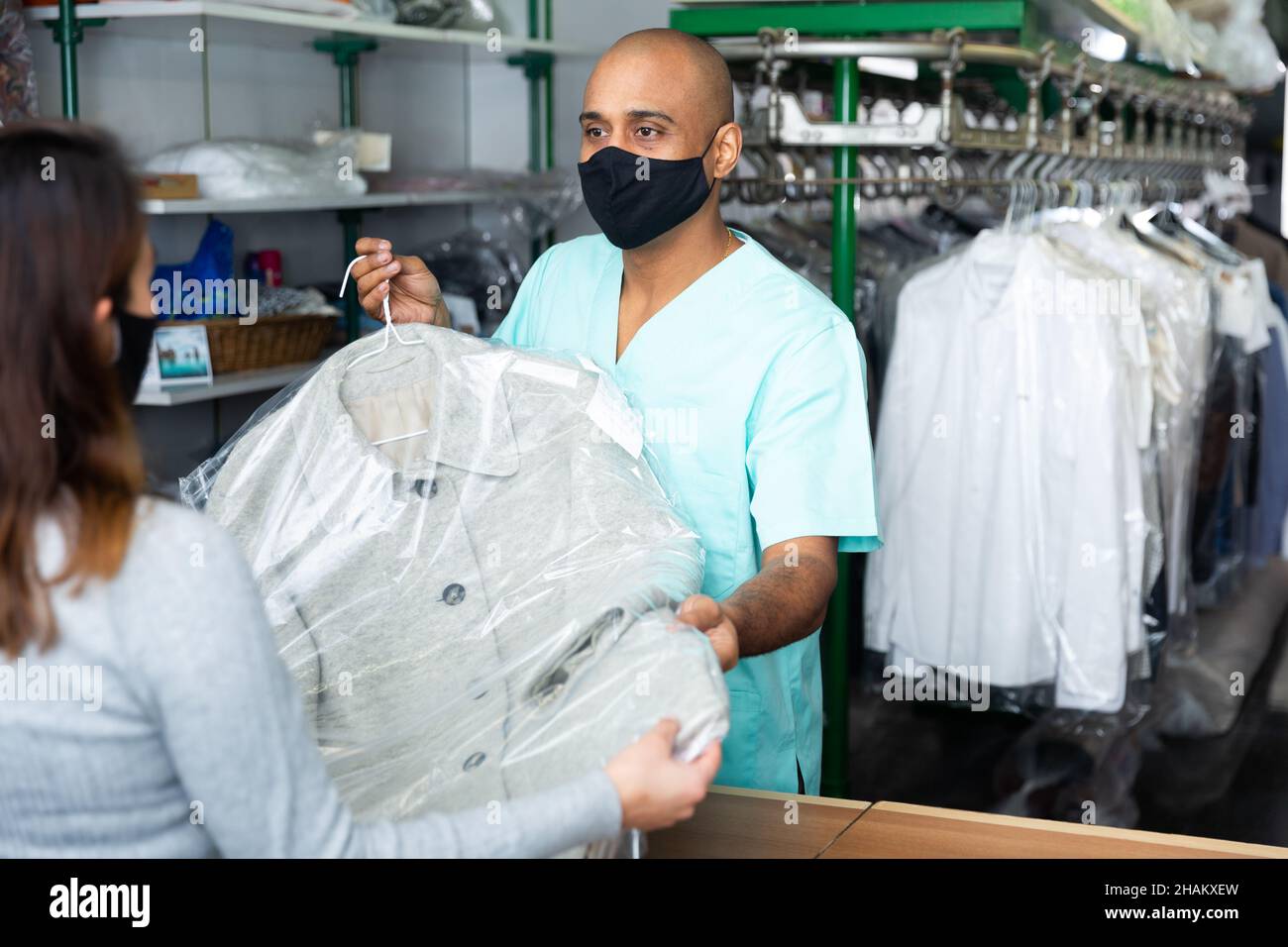 Man dry-cleaning worker giving clothes to customer Stock Photo - Alamy