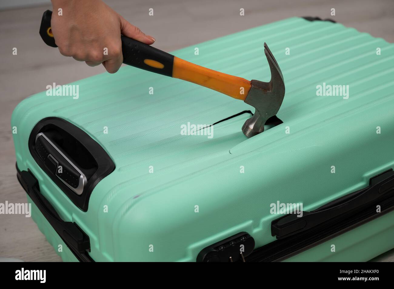 A woman hits a suitcase with a hammer on a white background Stock Photo ...