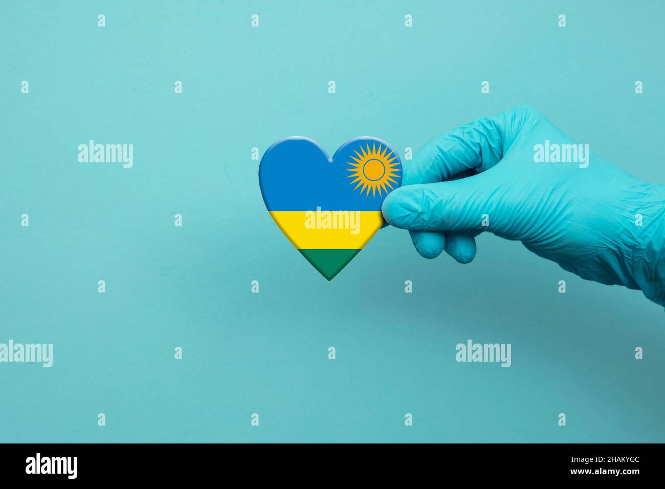 Medical workers hand wearing surgical glove holding Rwanda flag heart ...