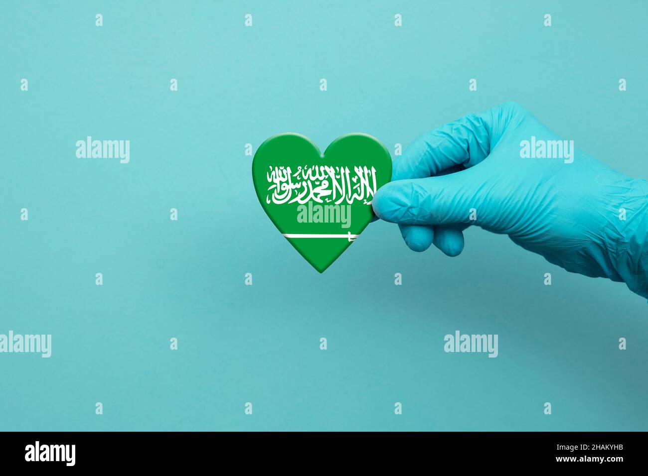 Medical workers hand wearing surgical glove holding Saudi Arabia flag ...