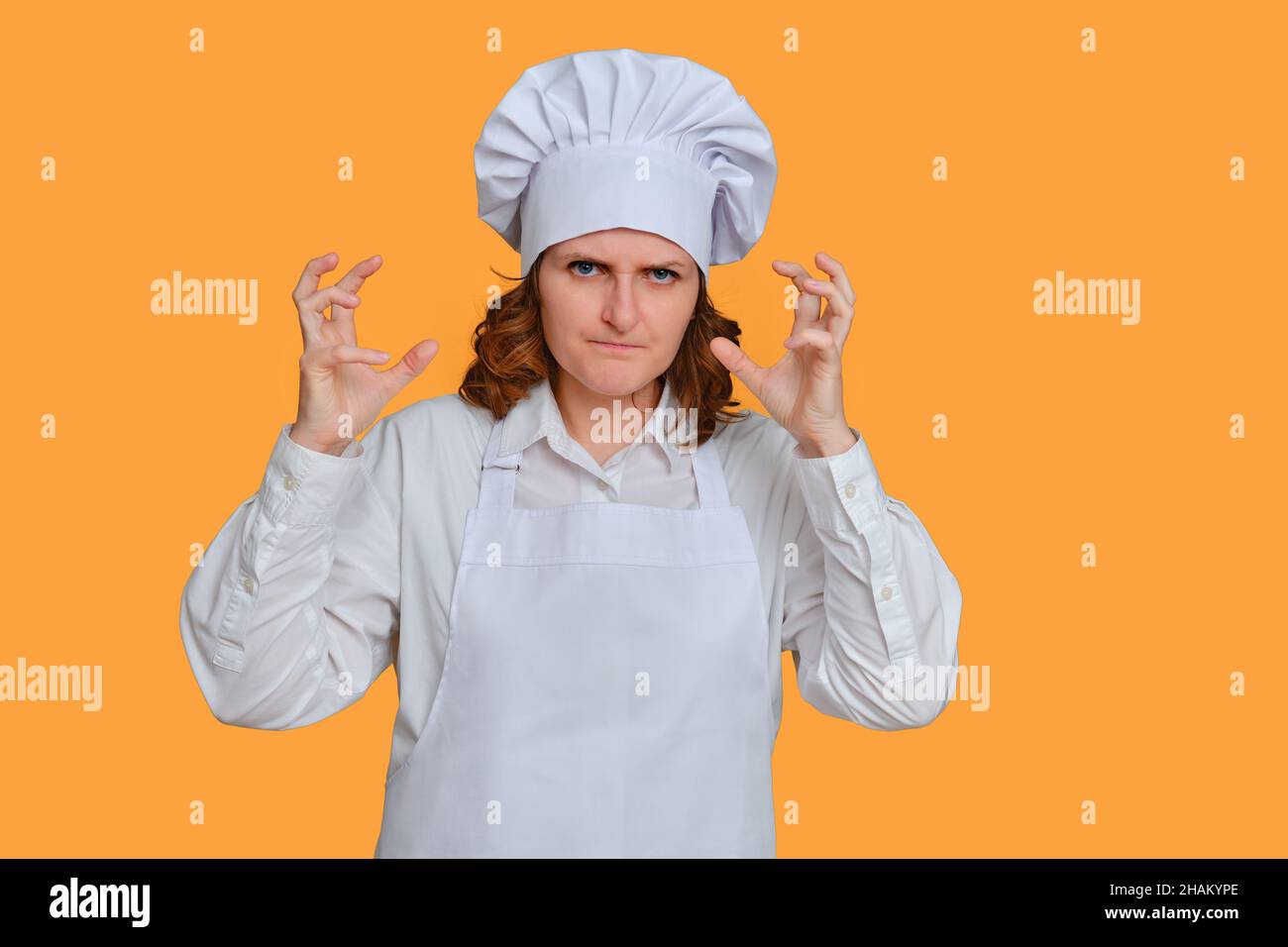 Angry female chef with emotions on her face on a studio background ...