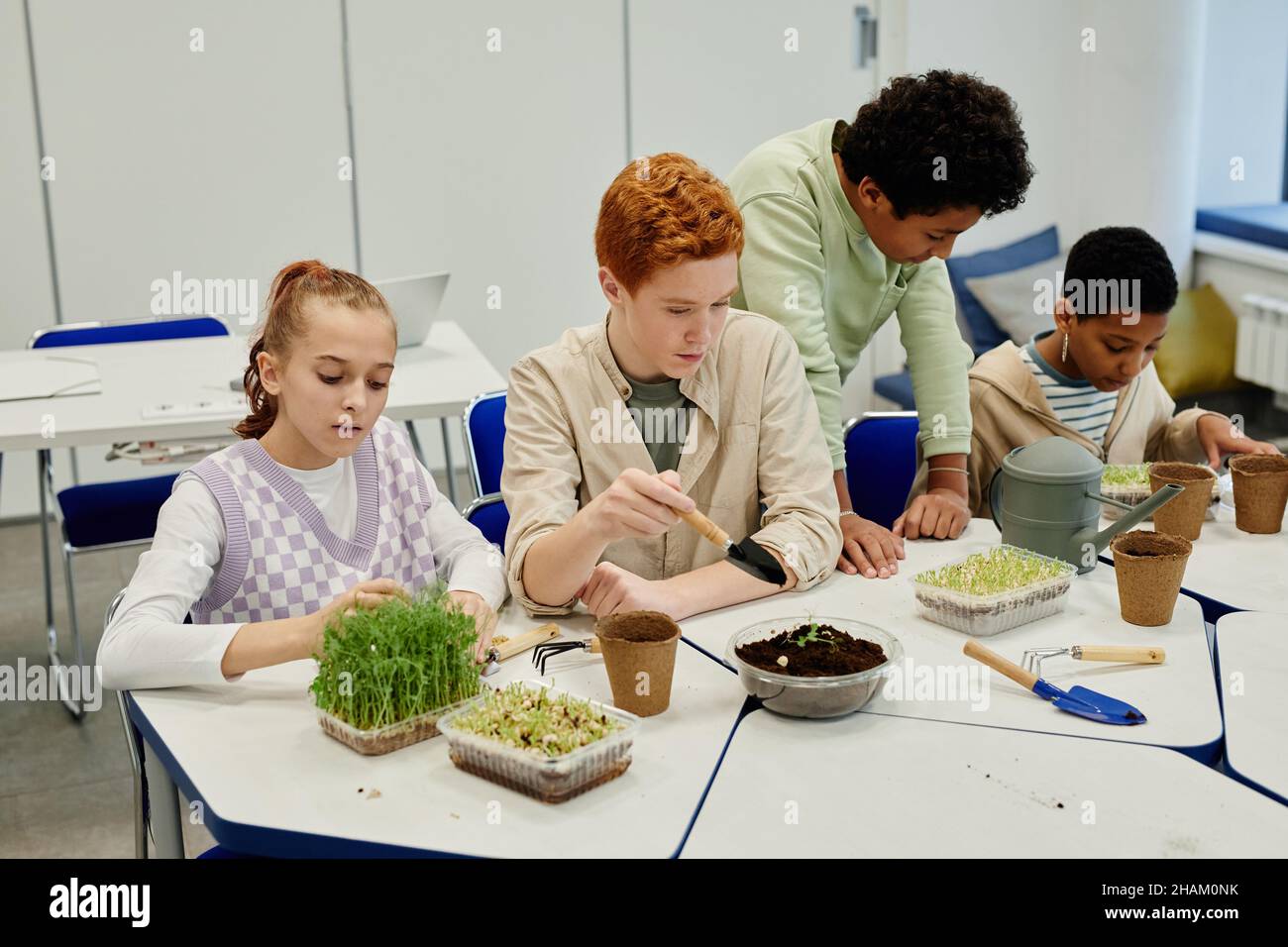 Diverse group of children planting seeds while experimenting at biology ...