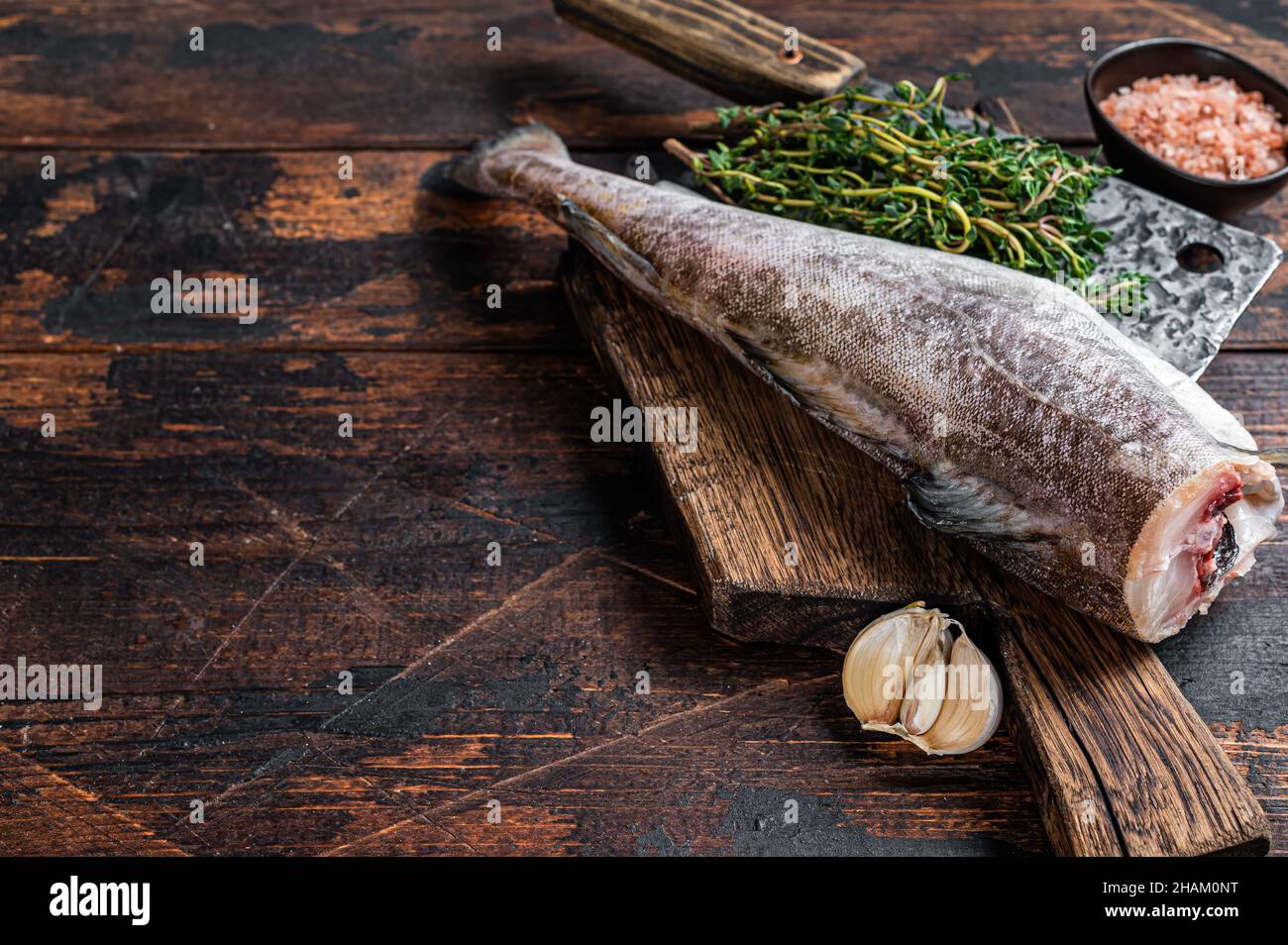 Fresh Raw cod or codfish fish on wooden board with cleaver. Dark Wooden ...