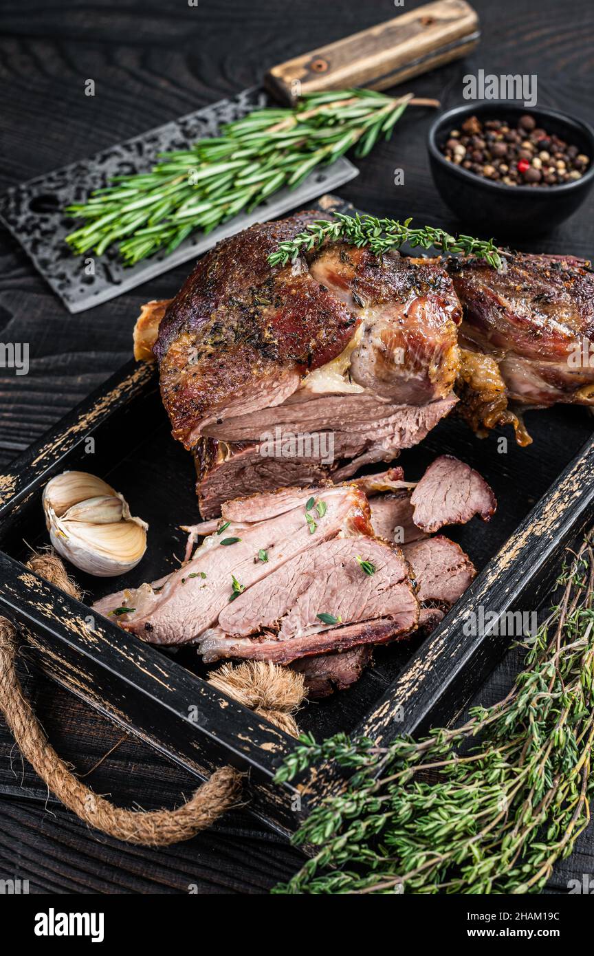 Roasted mutton lamb leg sliced in a wooden tray with meat cleaver ...