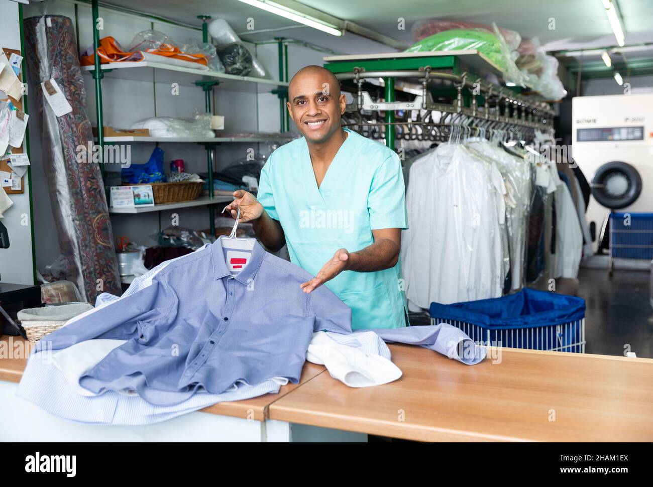 Laundry male worker demonstrates clean clothes Stock Photo - Alamy
