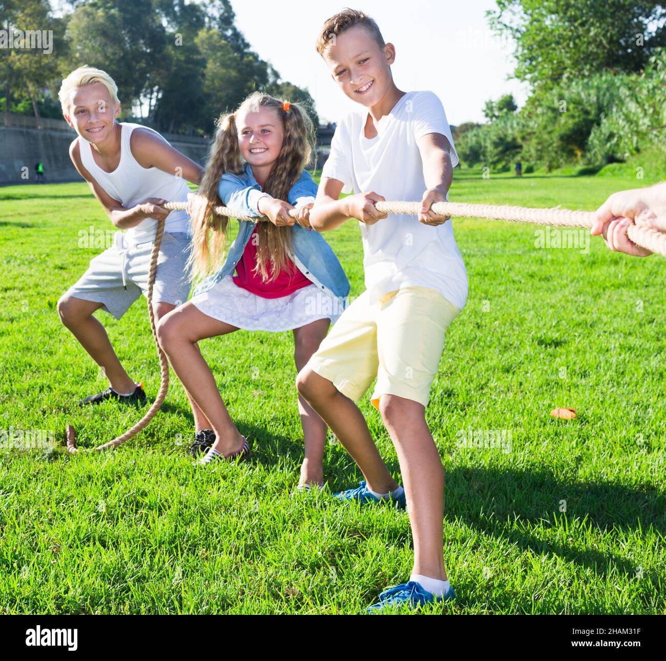 Happy kids tugging war in summer park Stock Photo - Alamy