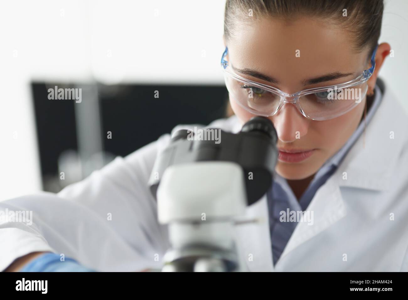 Female chemist investigate sample under microscope equipment in lab ...