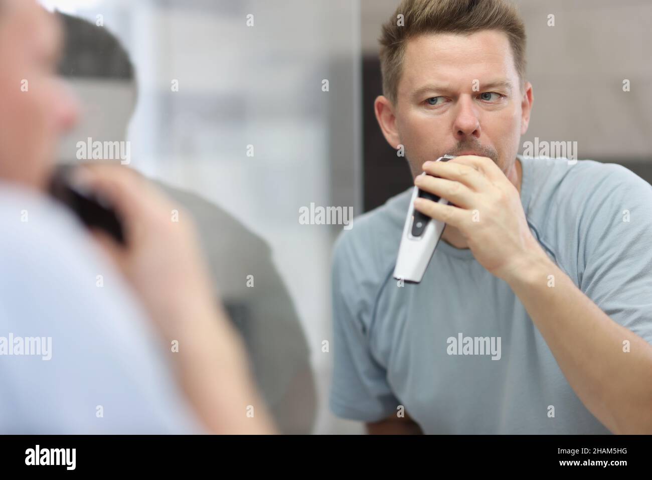 Middle aged man shaving beard with machine early in morning Stock Photo ...