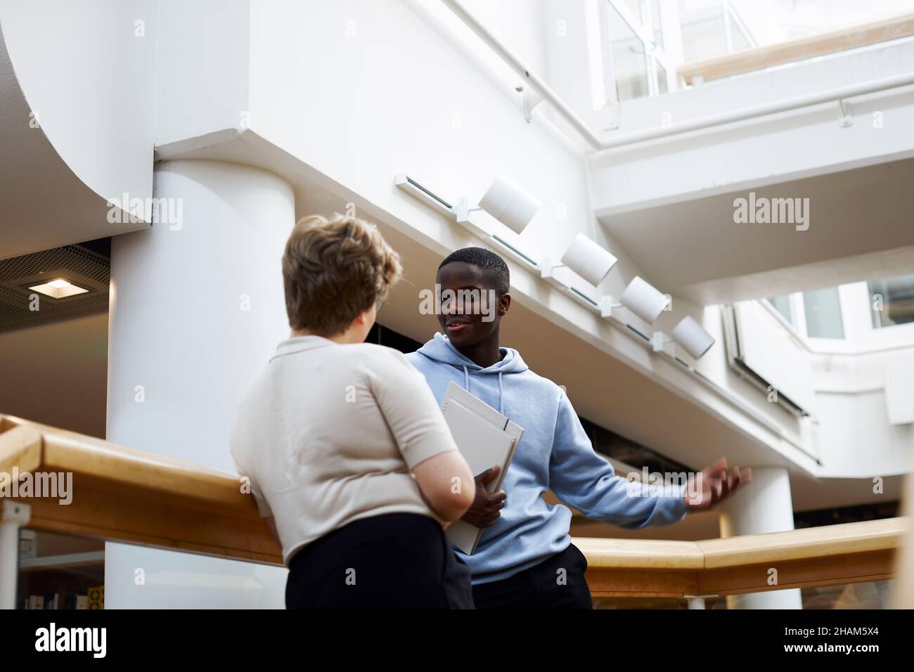 Two students talking in library Stock Photo - Alamy