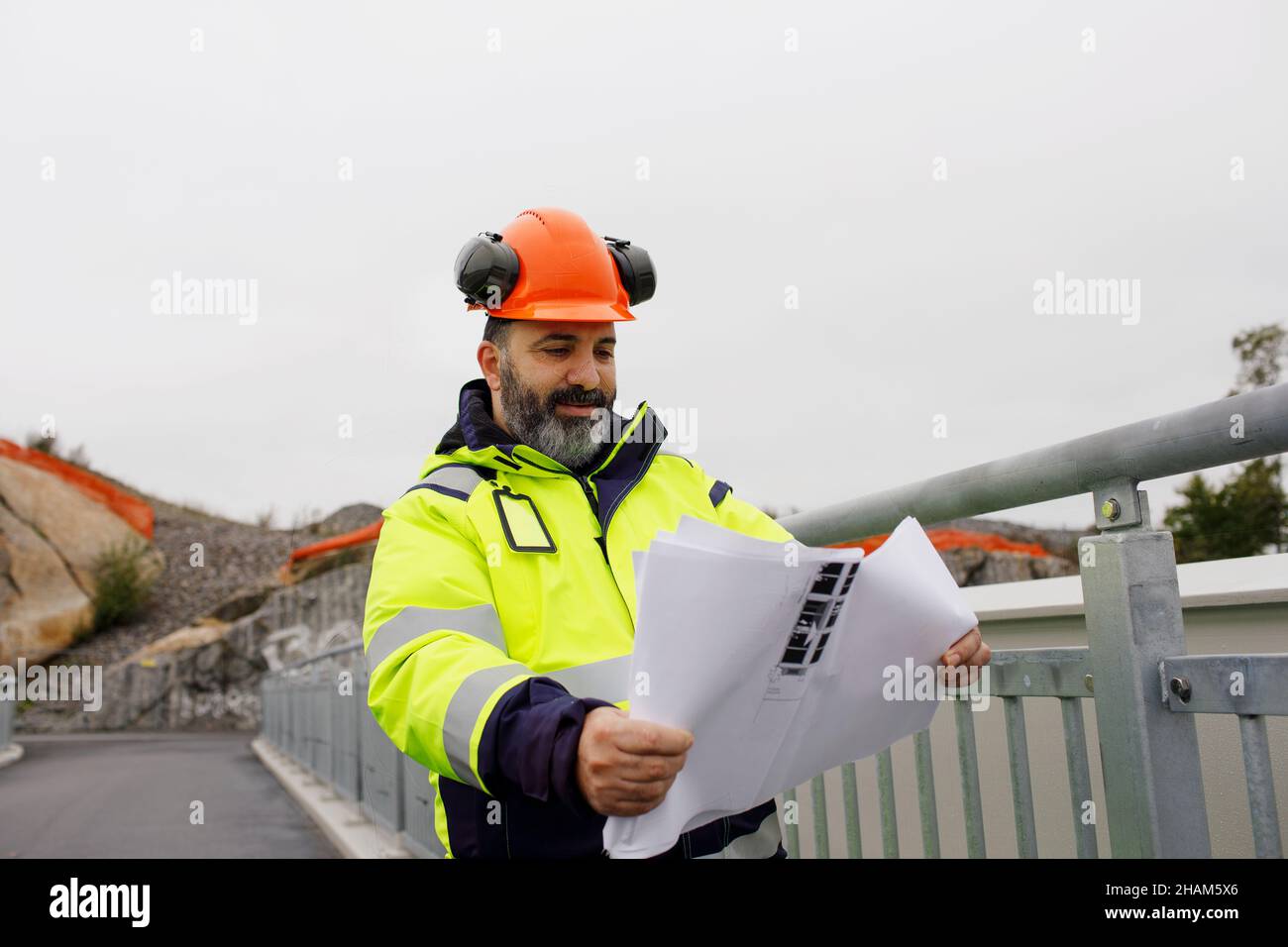 Male engineer in reflecting clothing looking at blueprint Stock Photo ...